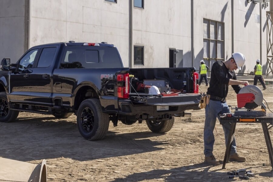 Man using a miter saw at a work site with a 2023 Ford Super Duty® truck ...