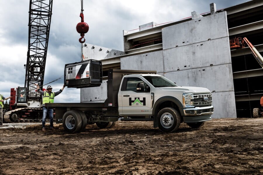 White Ford Super Duty Powerstroke with generator being lowered onto the bed